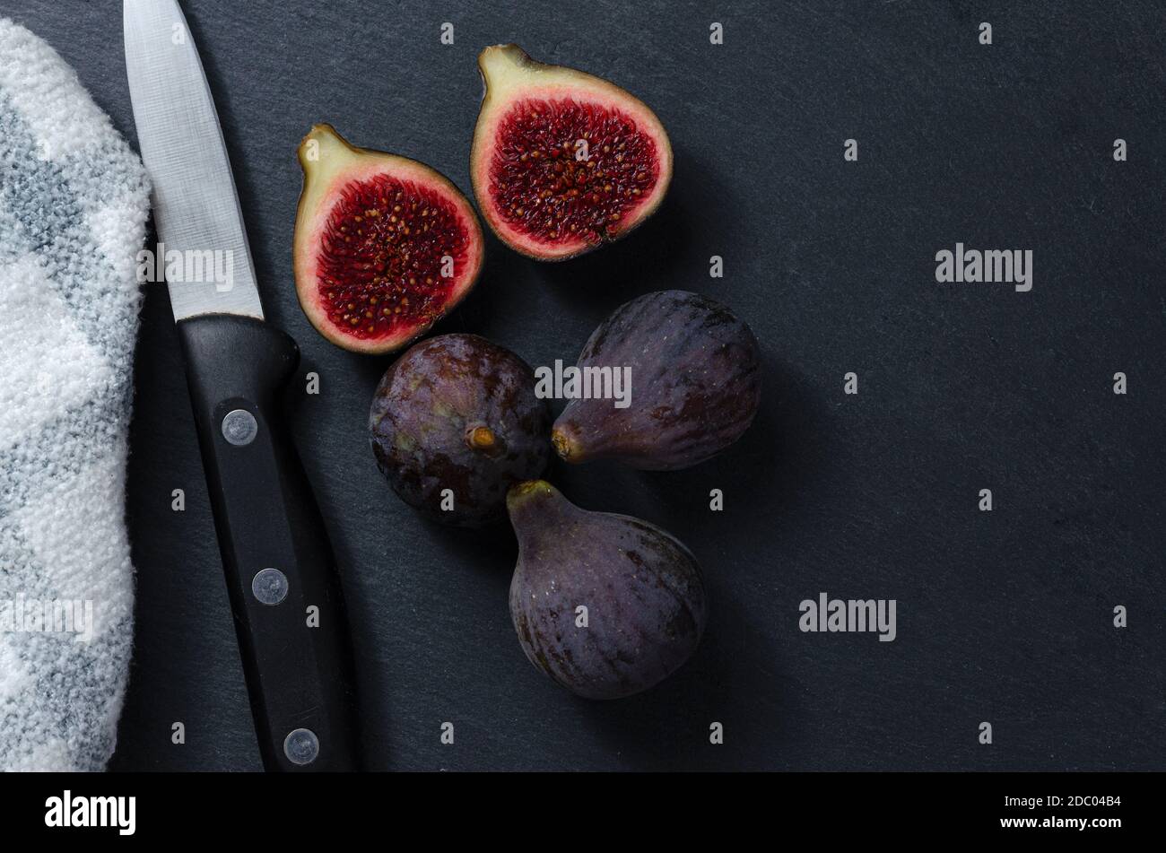 Still life of black figs. Three whole figs and one split fig with a ...