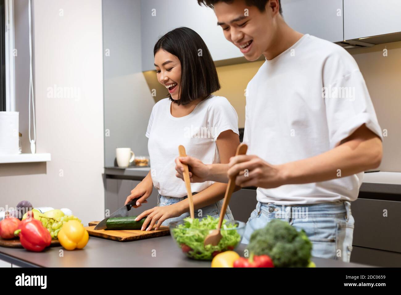 Asian Couple Cooks In Modern Kitchen, Laughing During Dinner ...