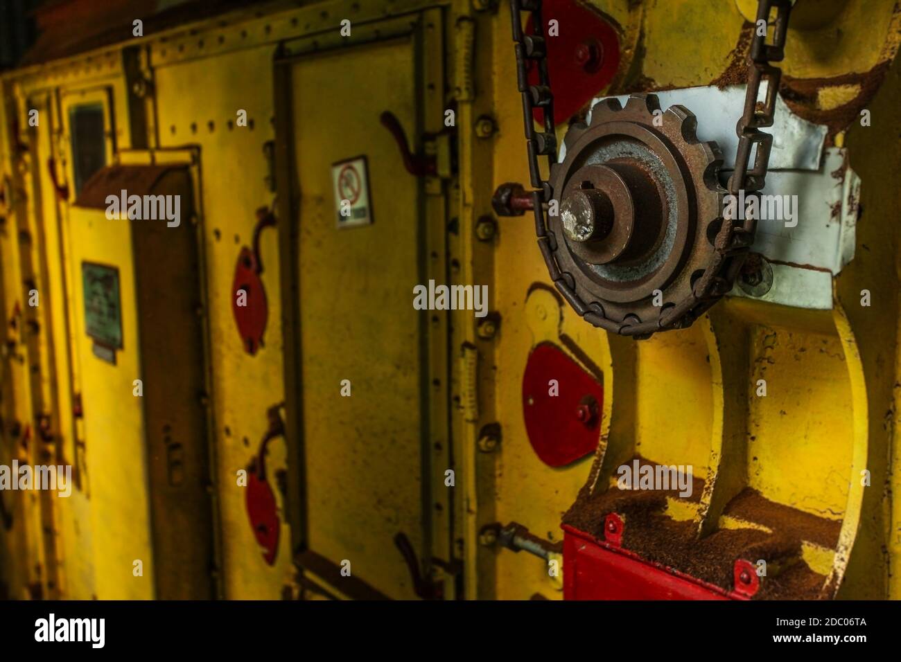 Old rusty cogwheel and chain on a yellow dryer machinery used in tea ...
