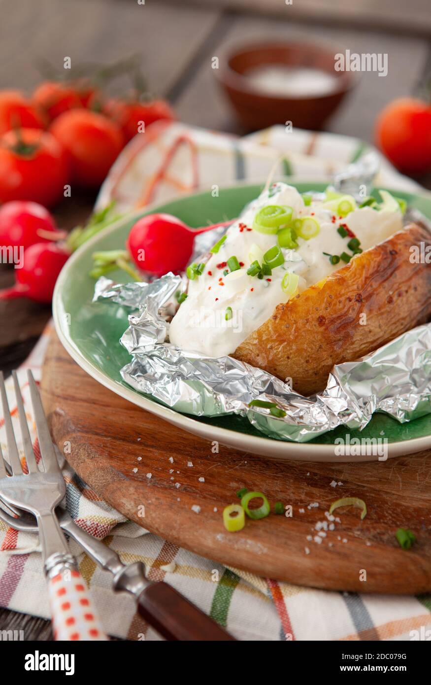Baked potato with sour cream and fresh herbs Stock Photo - Alamy