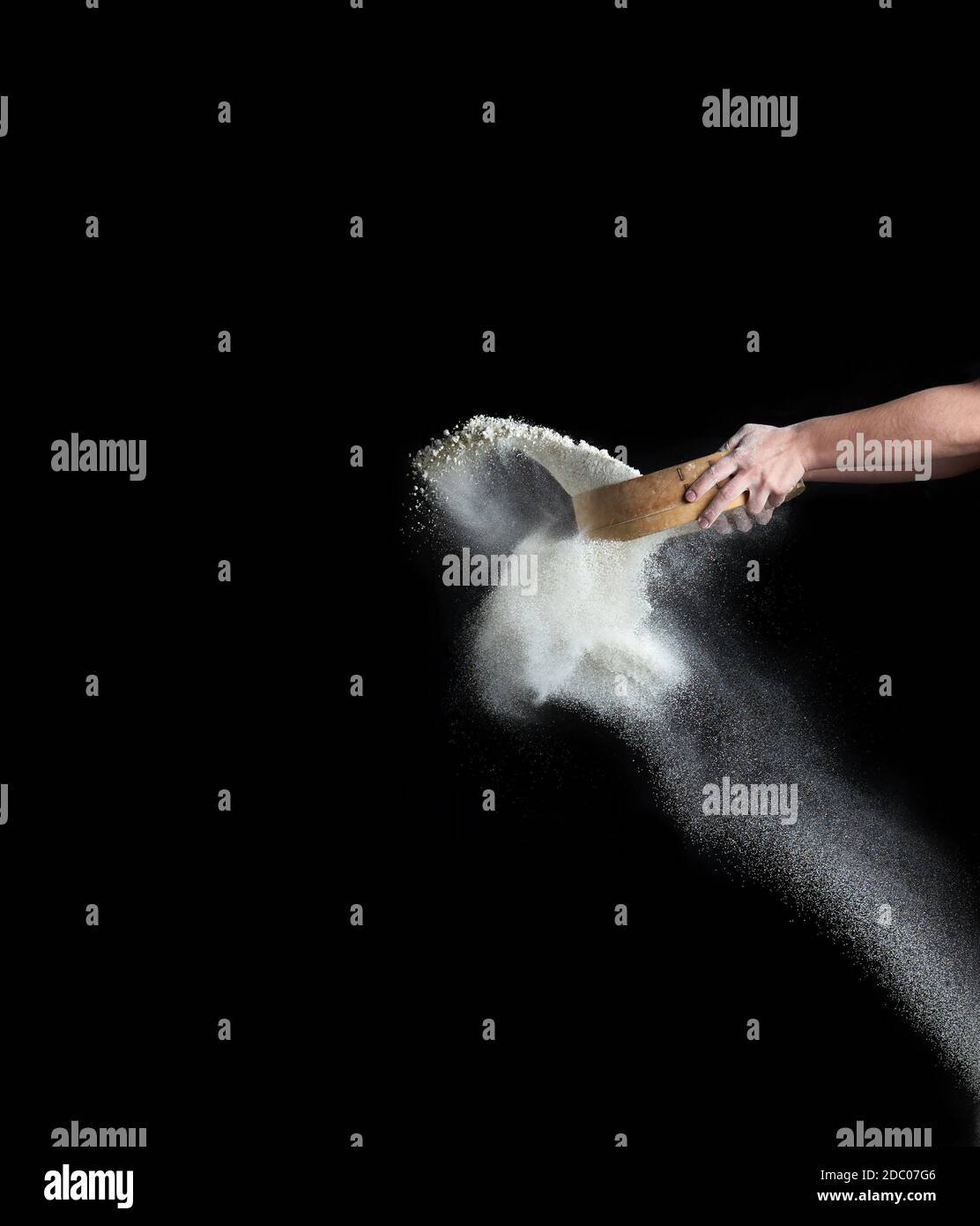 female hand sifts white wheat flour through a round wooden sieve on a ...