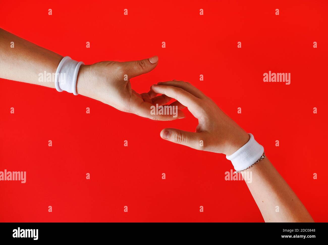 Give a helping hand. Hands with white bracelets reaching towards each ...