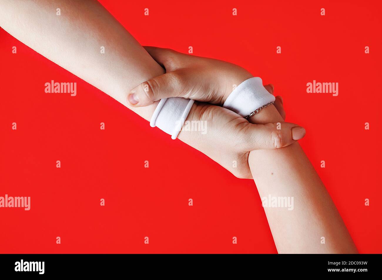 Helping hands concept. Hands with white bracelets on red backgroung ...