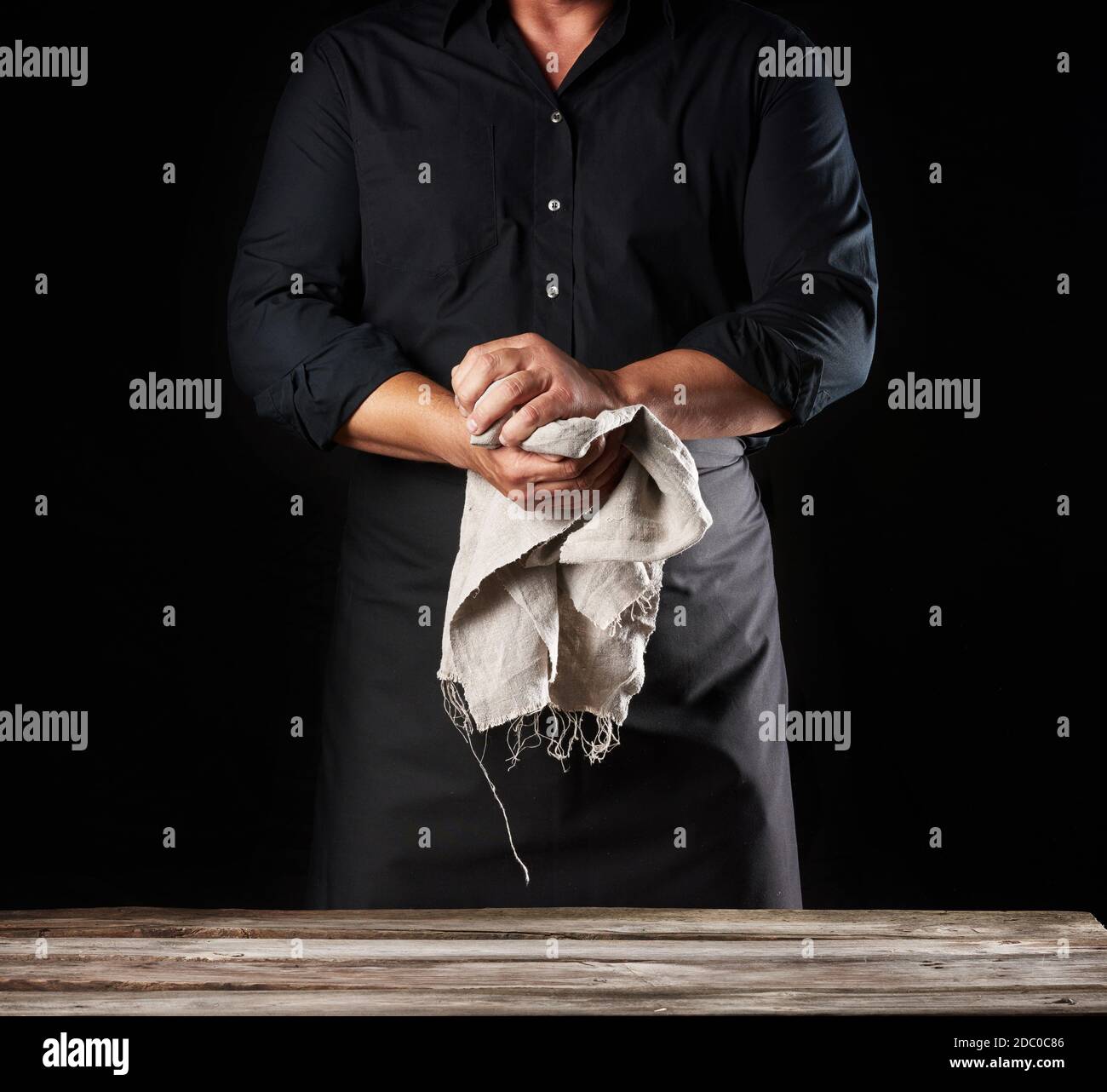 man in black uniform holds gray linen rag and wipes his hands, chef ...