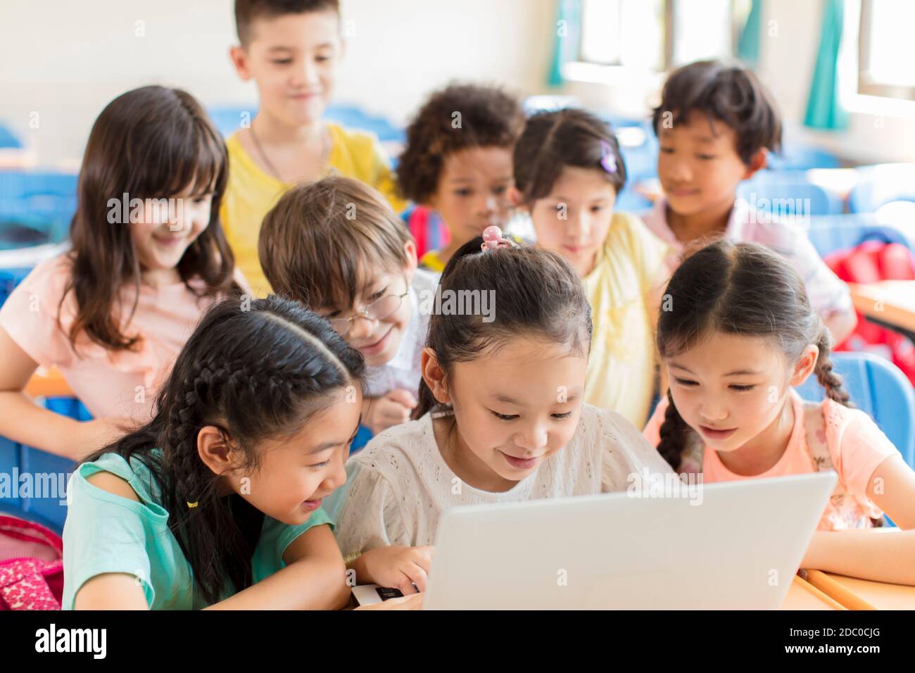 Happy children watching the laptop and discussing in the classroom ...