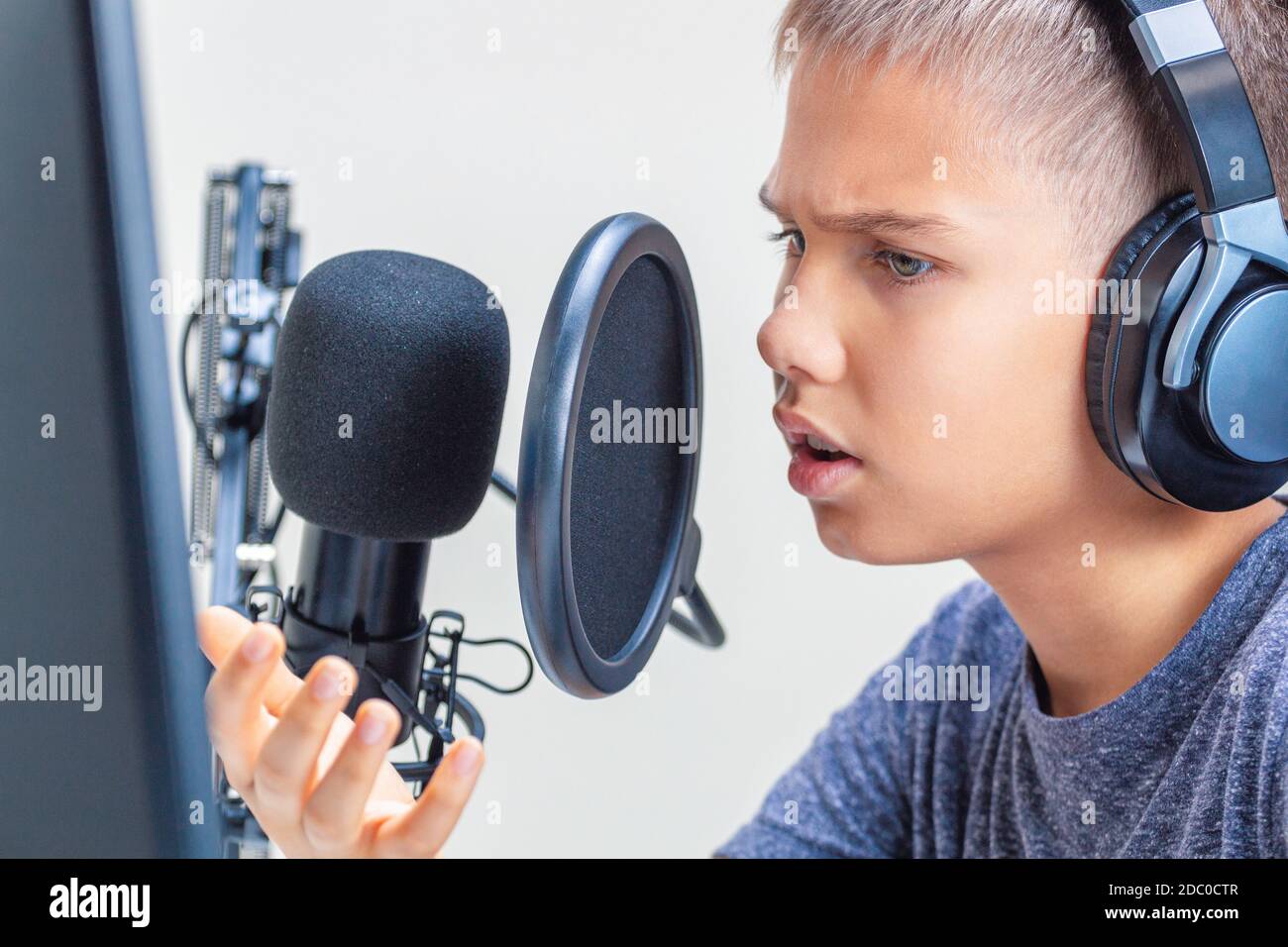 Teenager boy wearing headphones looking to computer monitor and talk ...