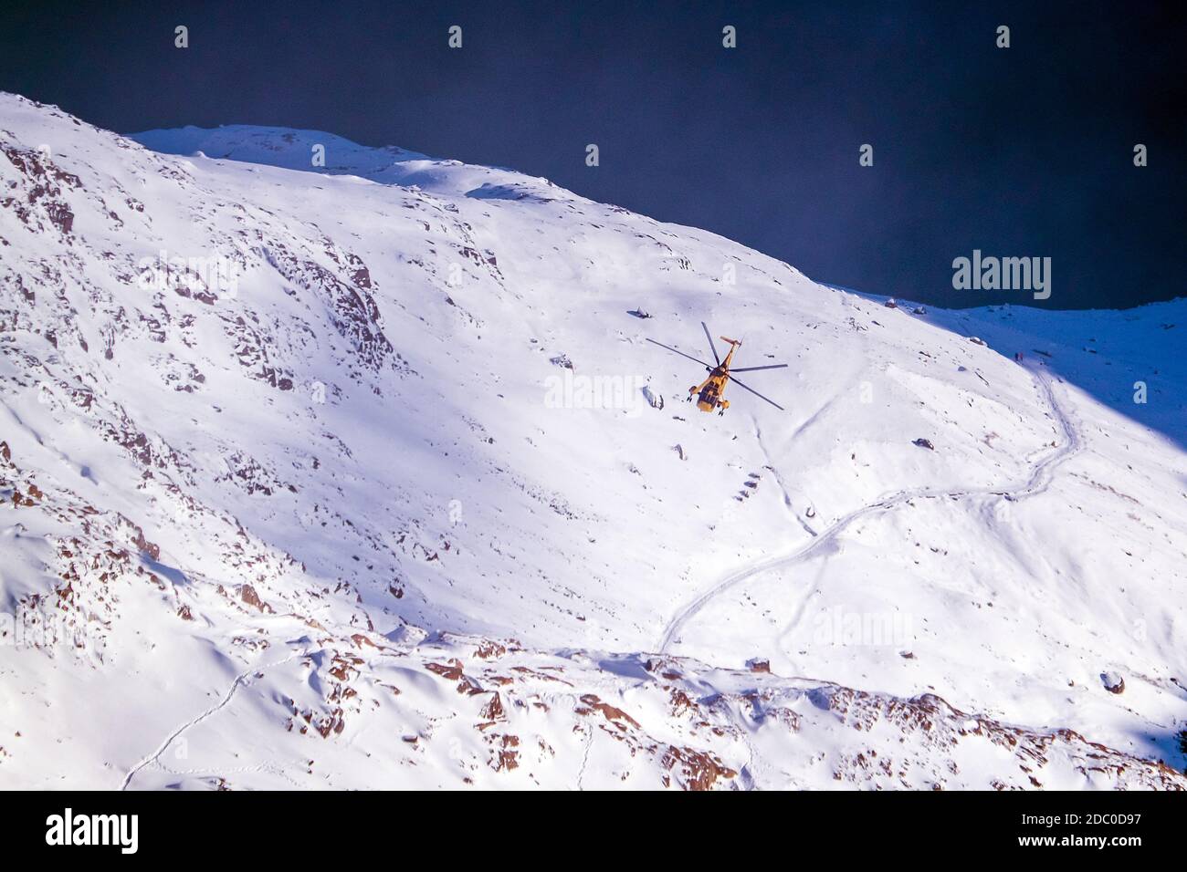 A Sea King mountain rescue helicopter flying over a snow-covered ...
