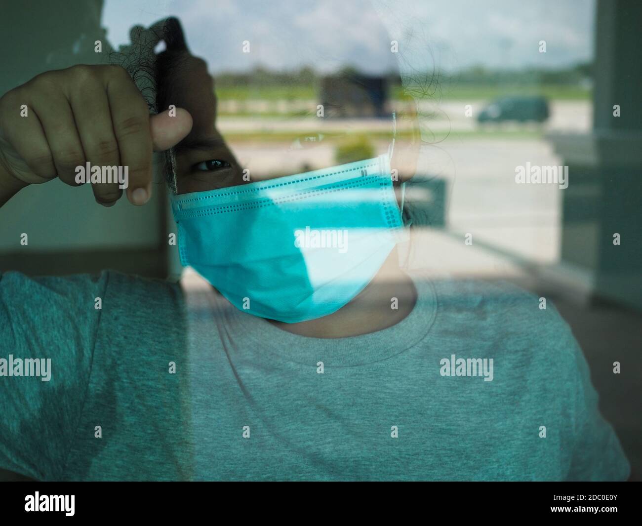 A woman wearing a protective mask looked out from the inside through ...