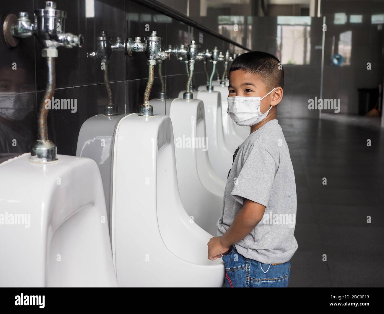 Boy wearing a protective face He is urinating in the public toilet ...