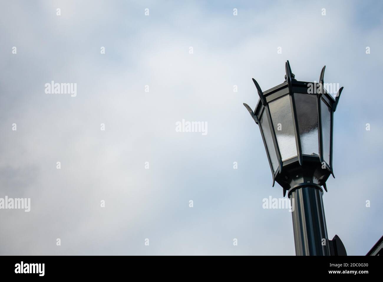 An Old Fashioned Black Metal Lamp Post on a Clear Blue Sky In Suburban ...