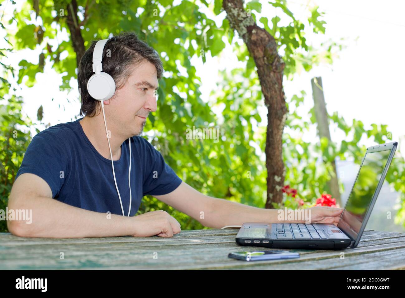 man sitting outdoor working with a laptop Stock Photo - Alamy