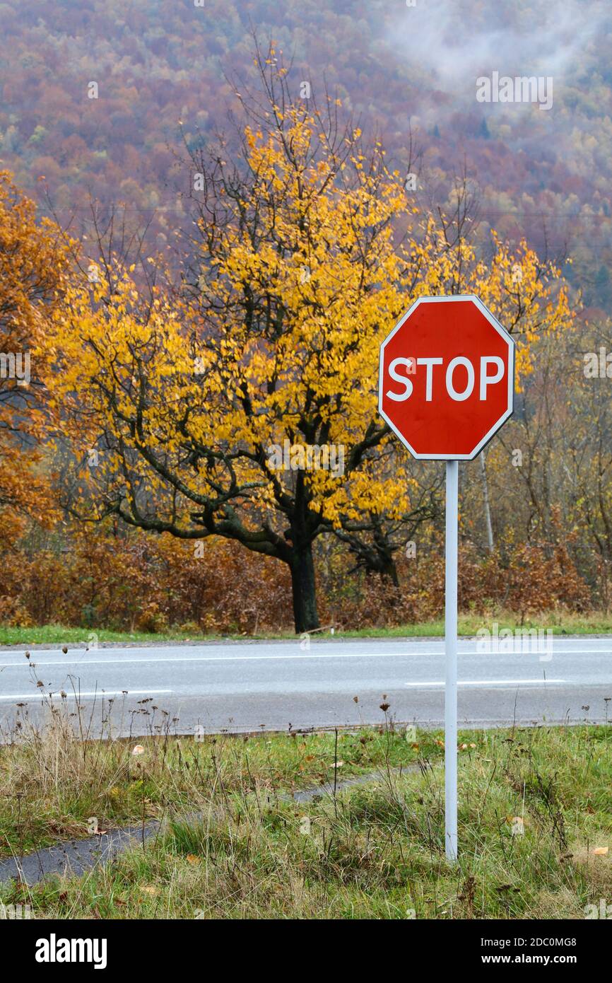 Close up road warning STOP sign over autumn mountain forest landscape ...