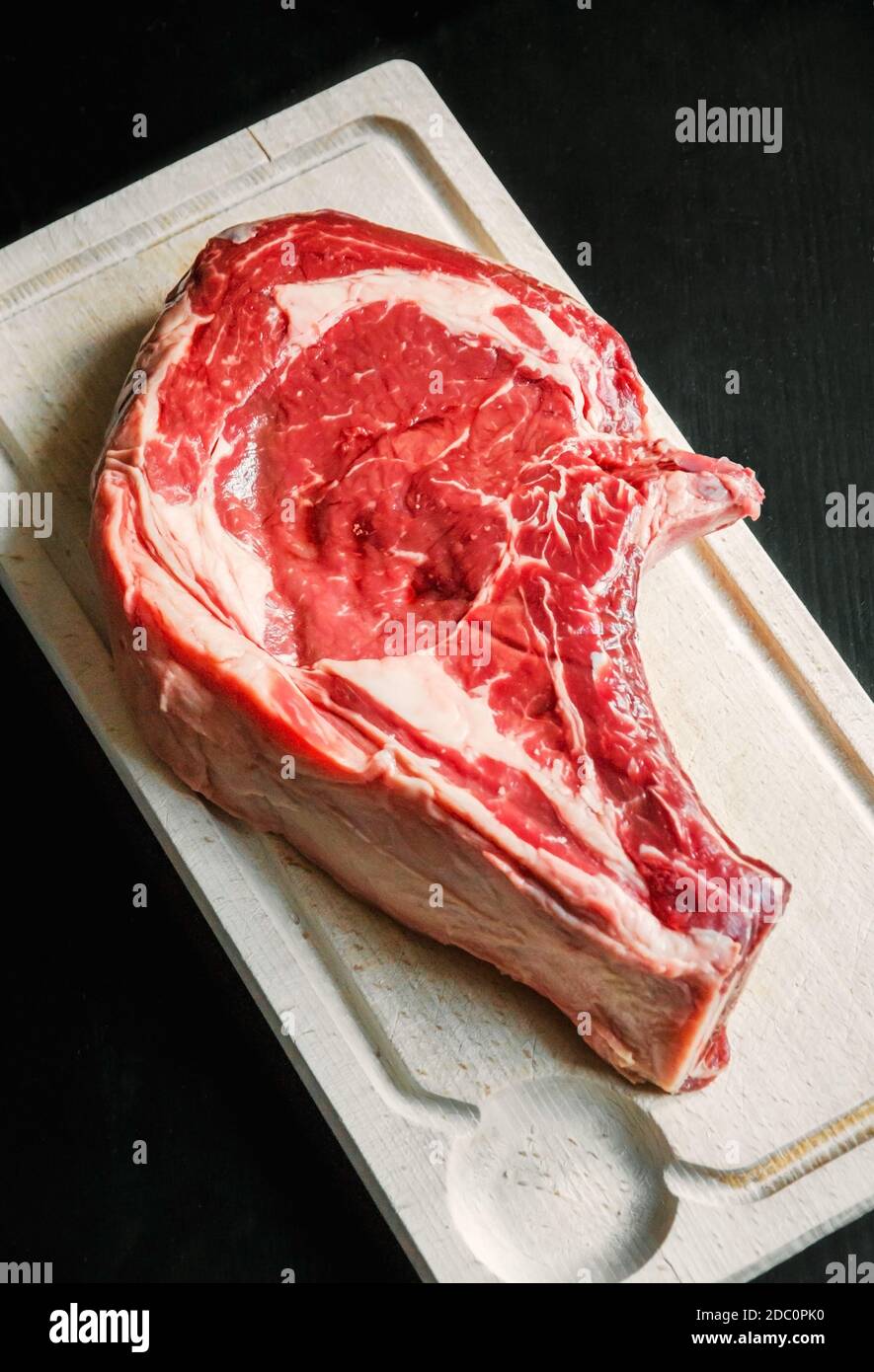 Raw beef prime rib on a cutting board isolated on black background ...