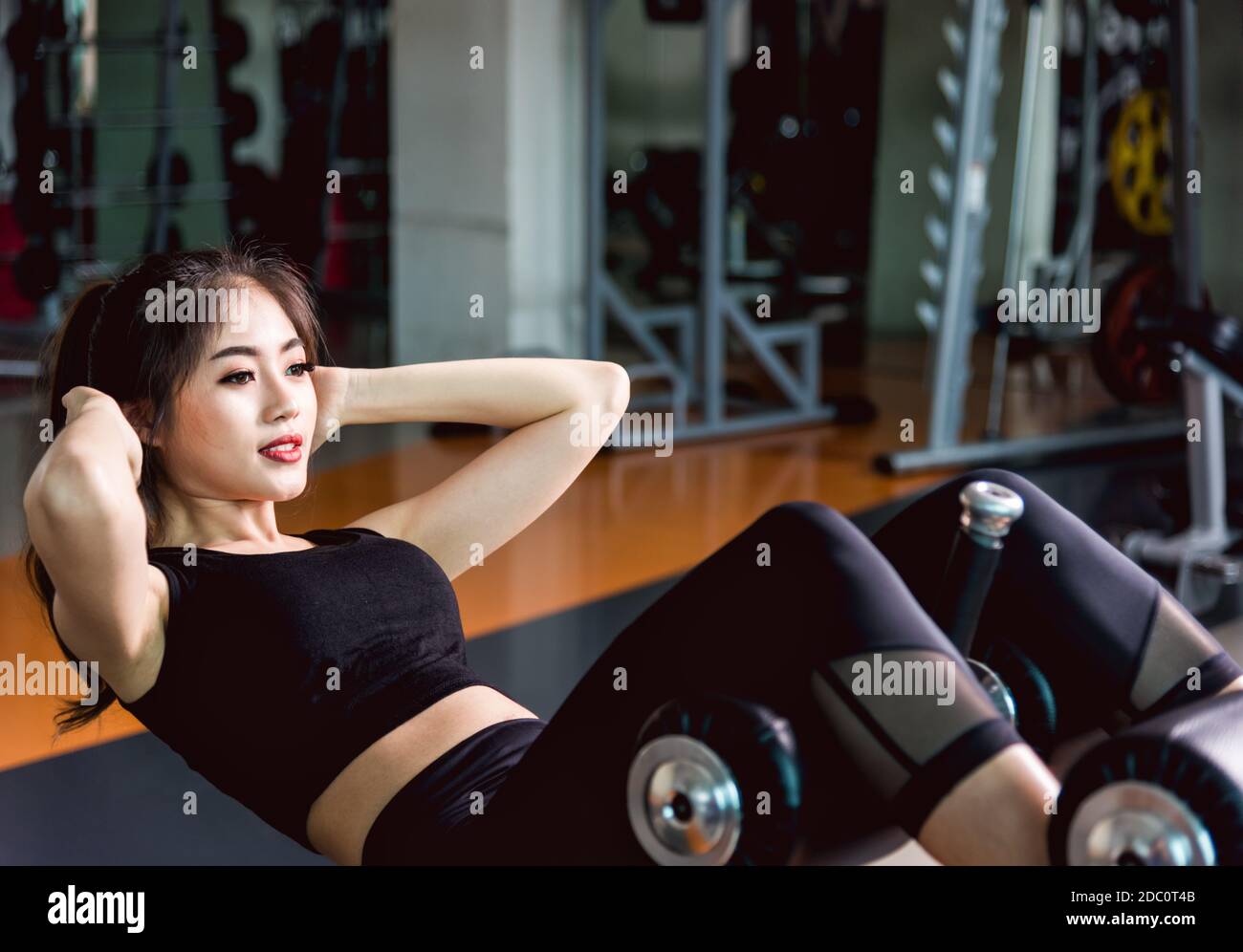 Young beautiful woman training using sit-ups machine workout at fitness ...