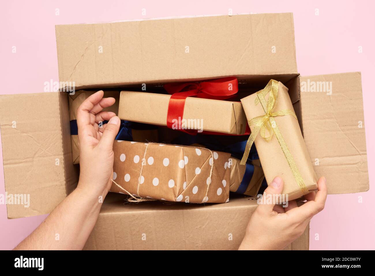 female hand takes out wrapped gifts from a cardboard box, top view ...