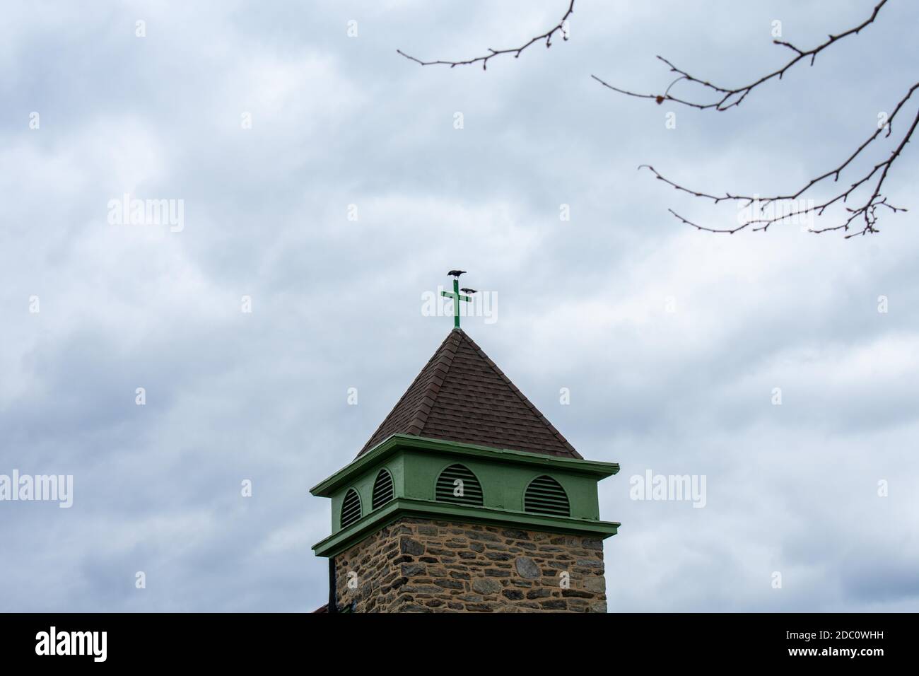 The Tower of a Cobblestone Church With a Cross on Top on a Cloudy ...