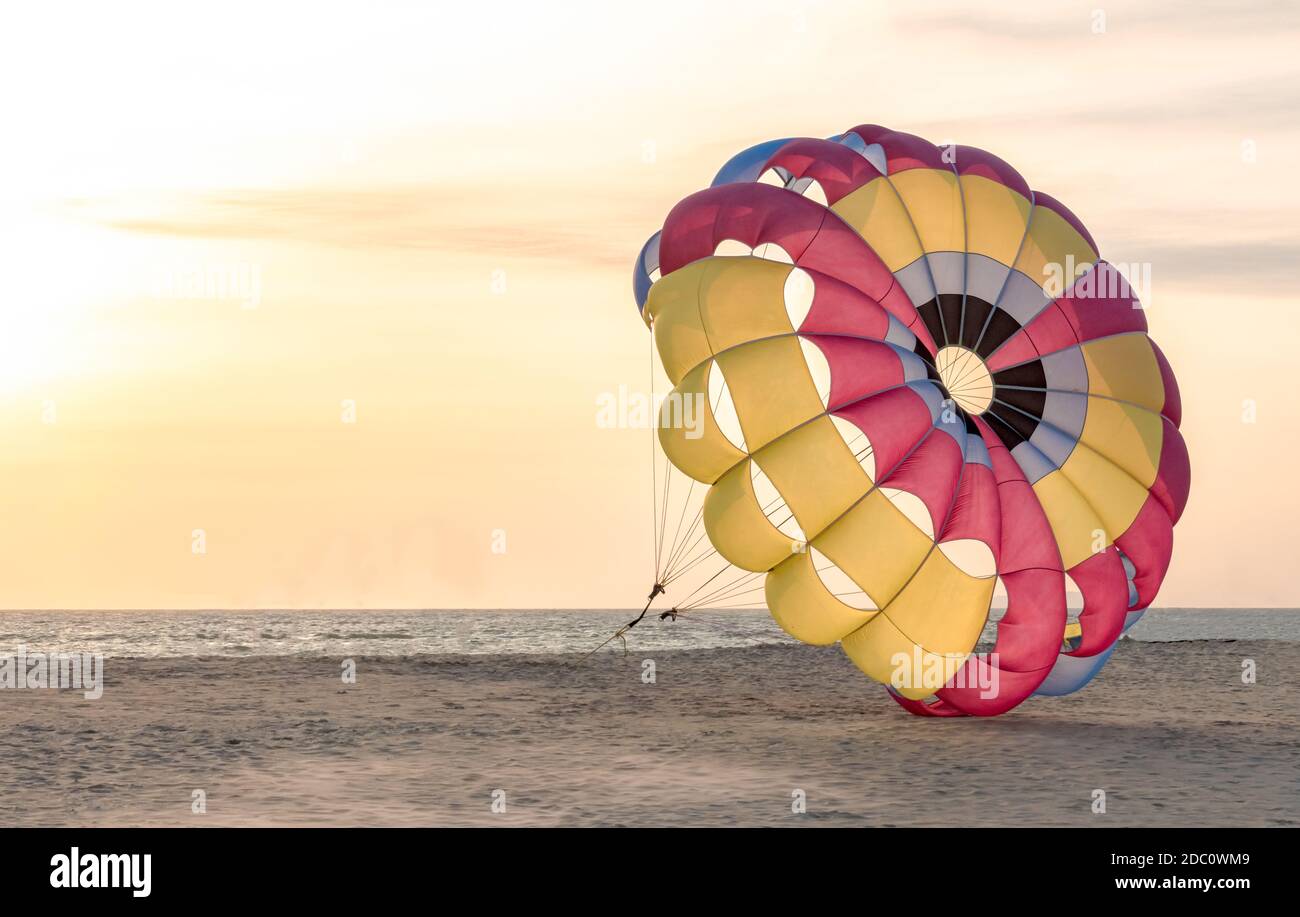 Colorful parasailing parachute fully blown up and anchored on secluded ...