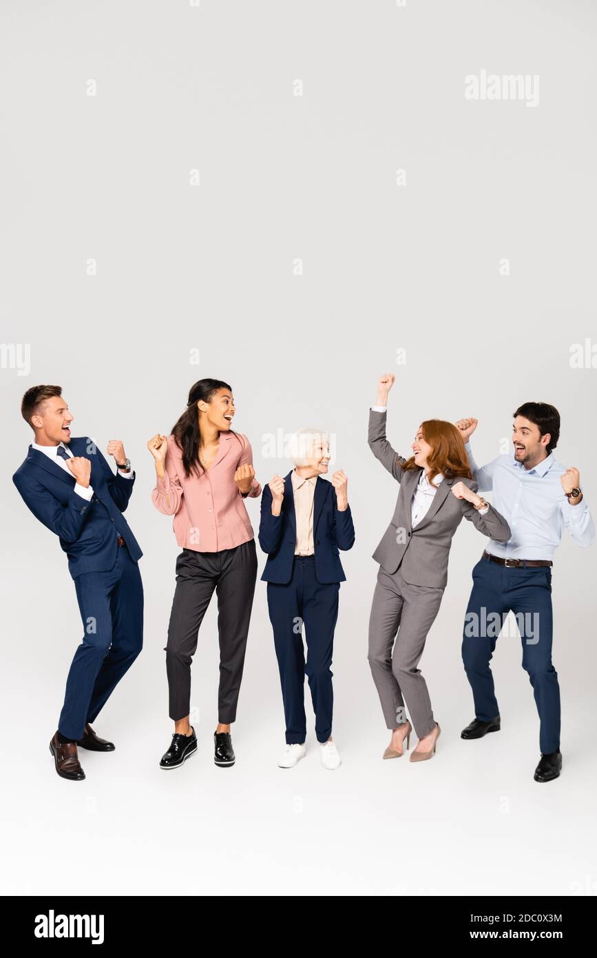 Positive multicultural businesspeople showing yeah gesture on grey ...