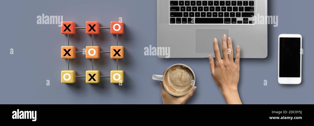 cube grid with tic tac toe game besides laptop and coffee on a grey ...