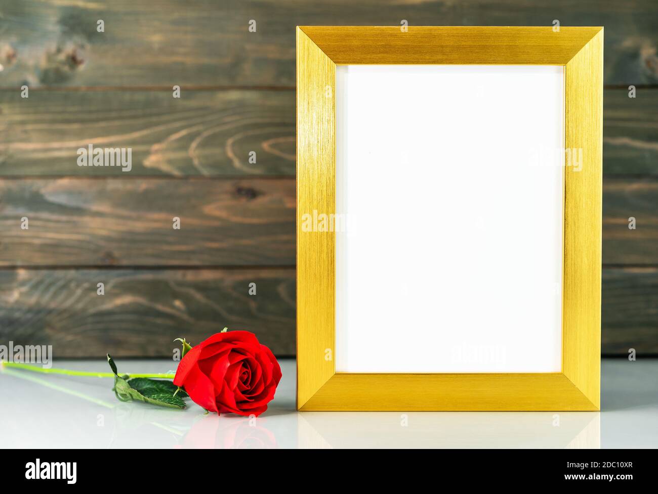 Picture mock up with golden frame and red roses flowers on table with ...