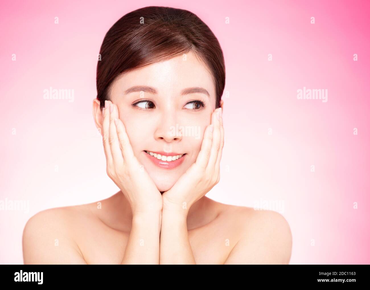 Beautiful young woman touching her face looking to the side Stock Photo ...