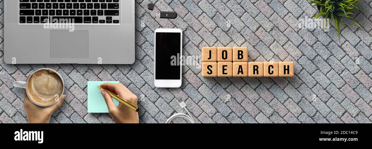 hand is typing on a computer keyboard and cubes with message JOB SEARCH ...
