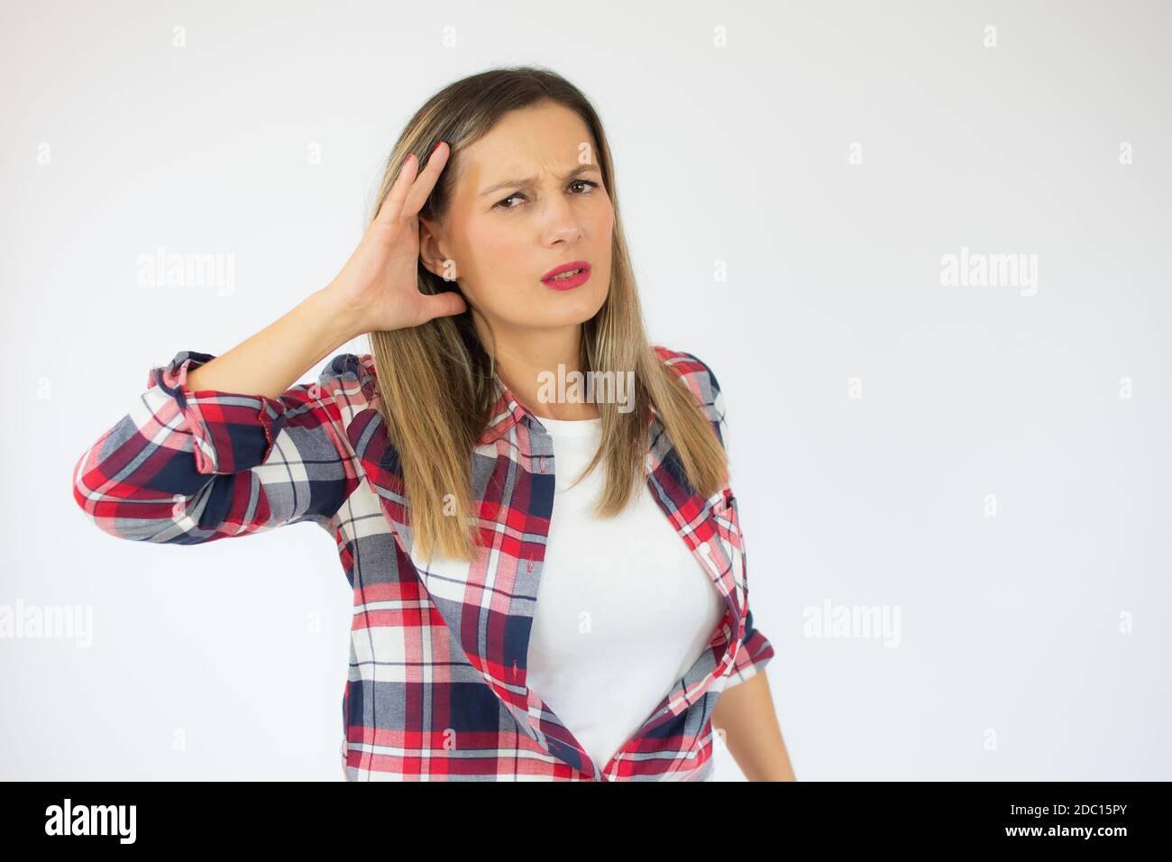 Young woman over isolated white background listening to something by ...