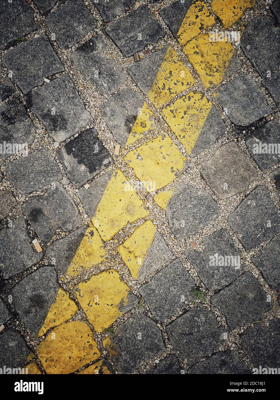A yellow line marking on cubical stone pavement Stock Photo - Alamy