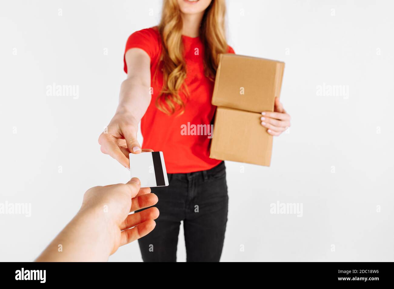 Courier girl in uniform holding cardboard boxes and a credit card on a ...