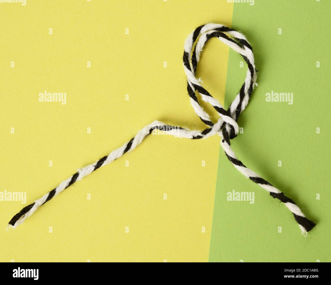 white-black rope on a green background twisted into a loop, close up ...