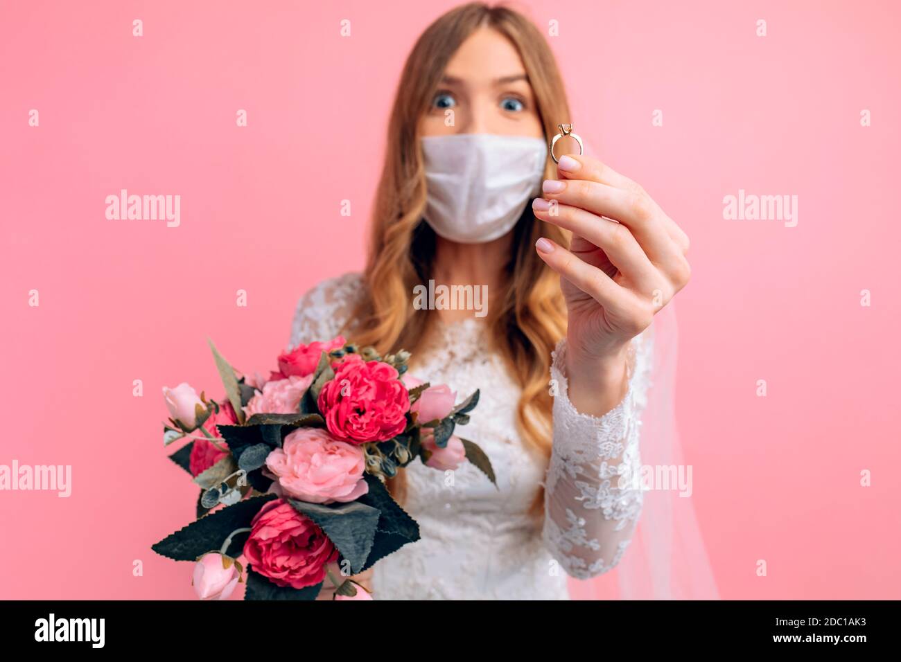A bride in a wedding dress and a medical protective mask on her face ...
