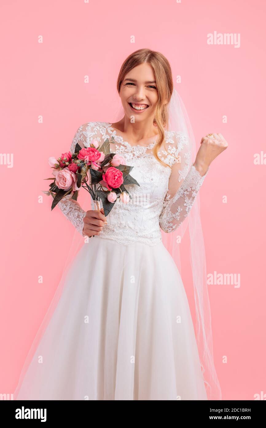 Happy excited bride with a bouquet of flowers in a wedding dress ...