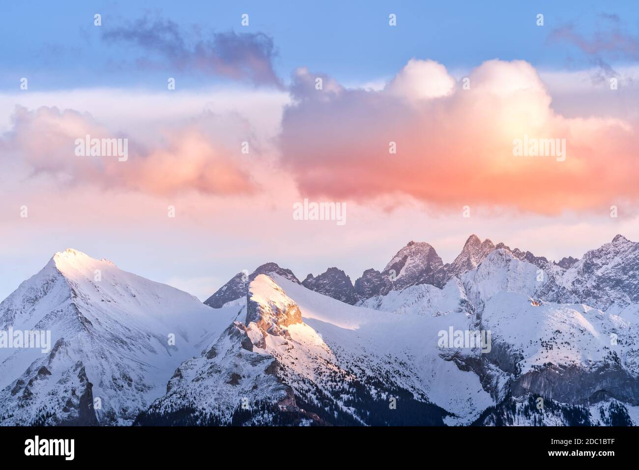 Sunset with dramatic sky and snowy mountain peaks illuminated by ...