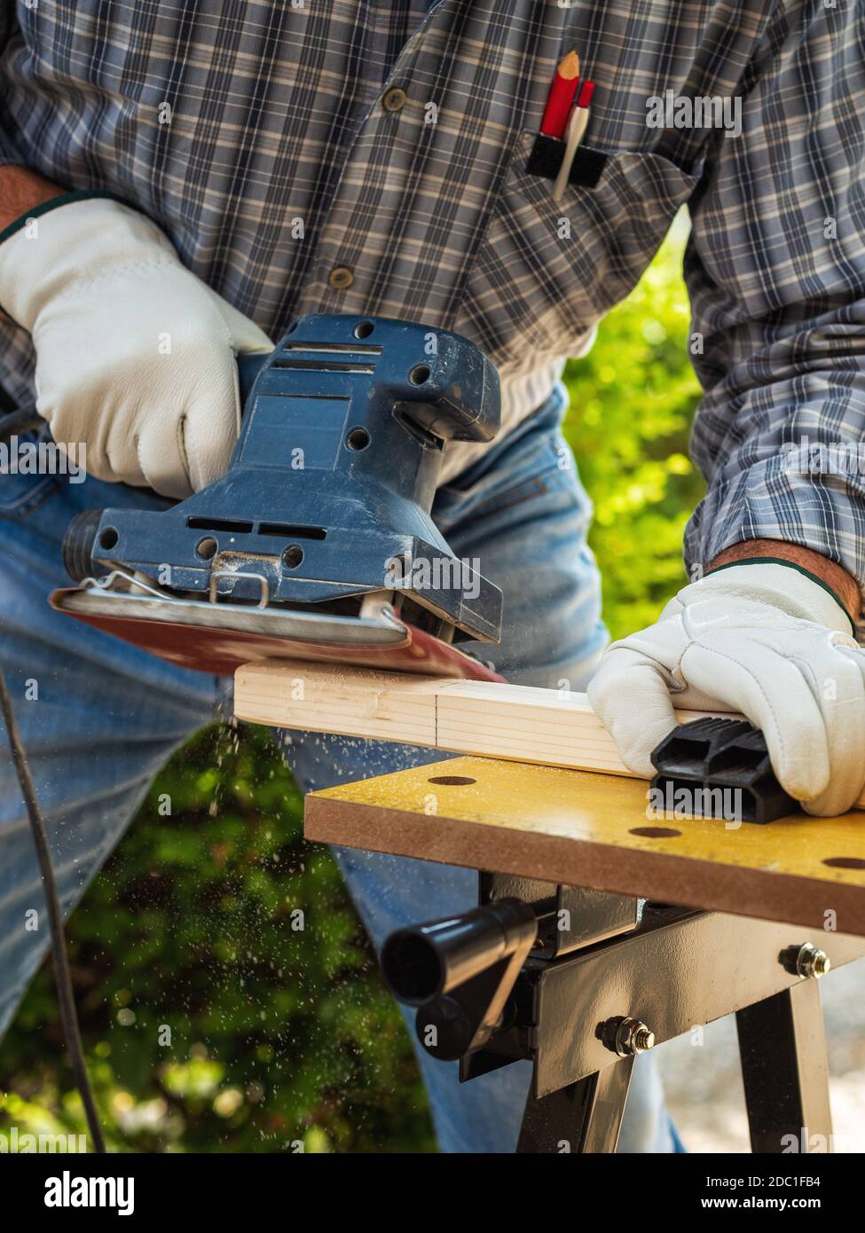 Close-up. Carpenter with his hands protected by gloves with the ...