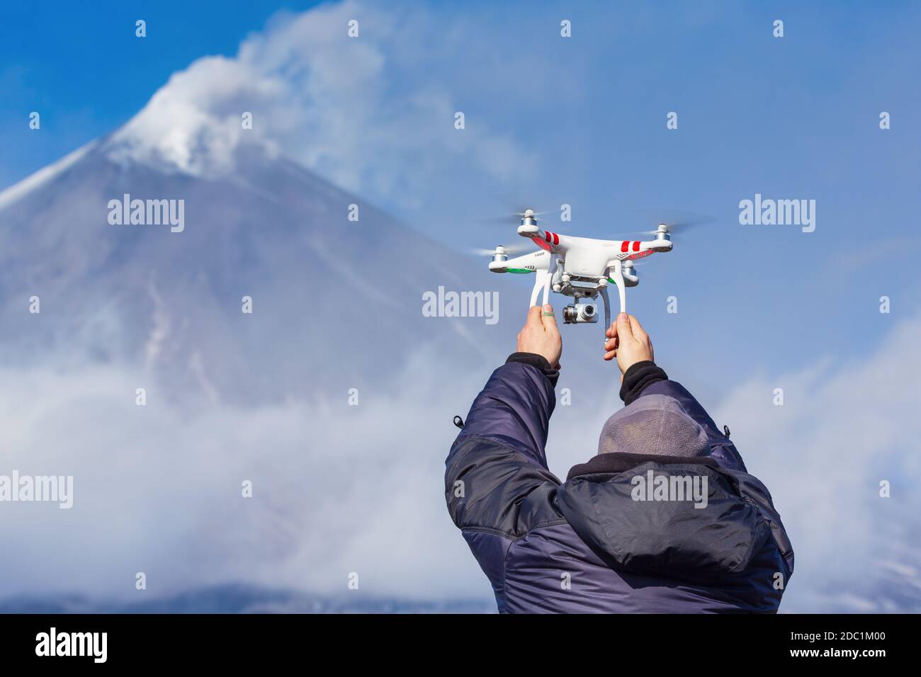Drone operator catches flying quadcopter UAV on background volcano ...