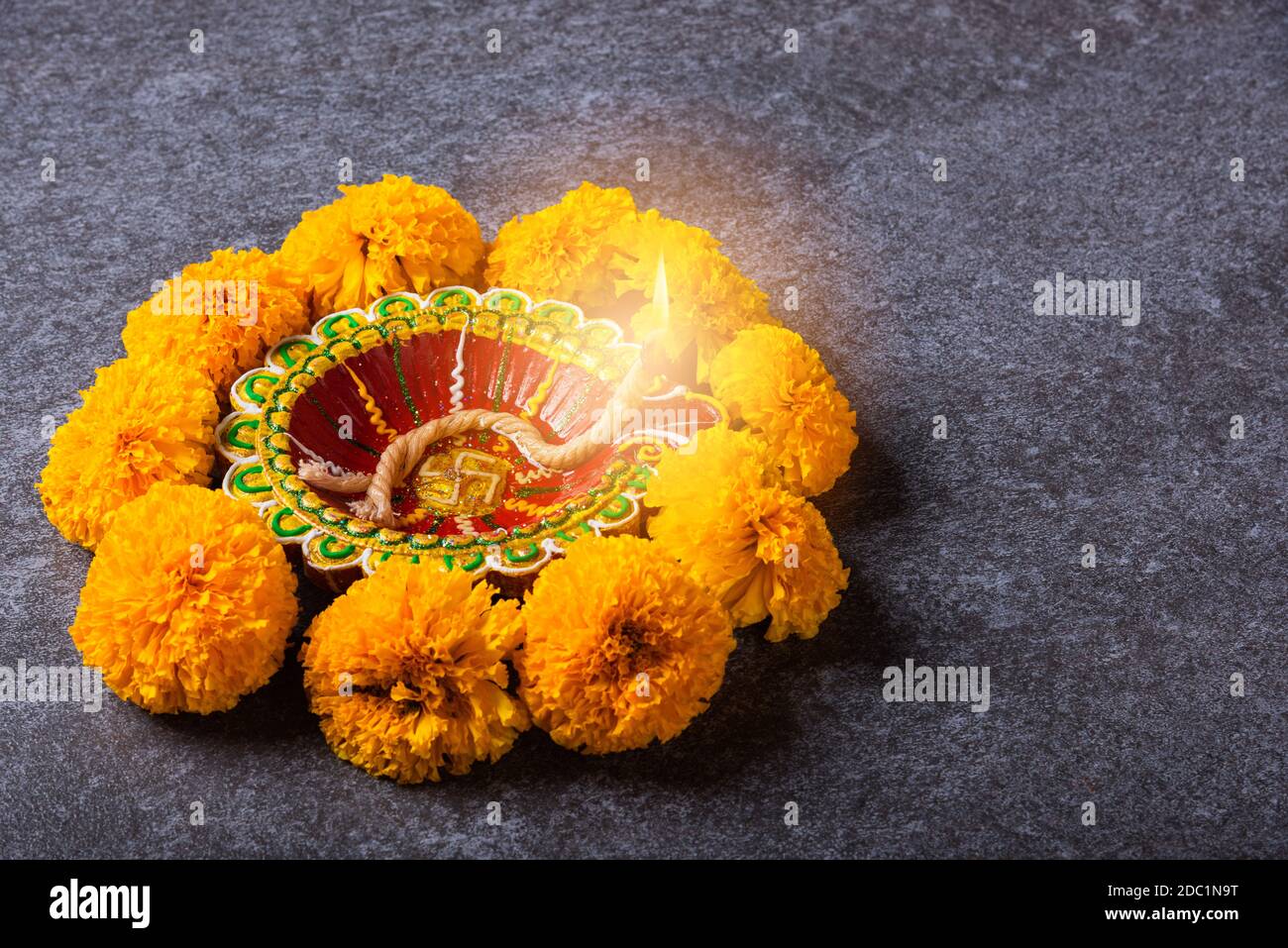 Top view overhead clay lit Diya or oil lamp and yellow flower, studio ...
