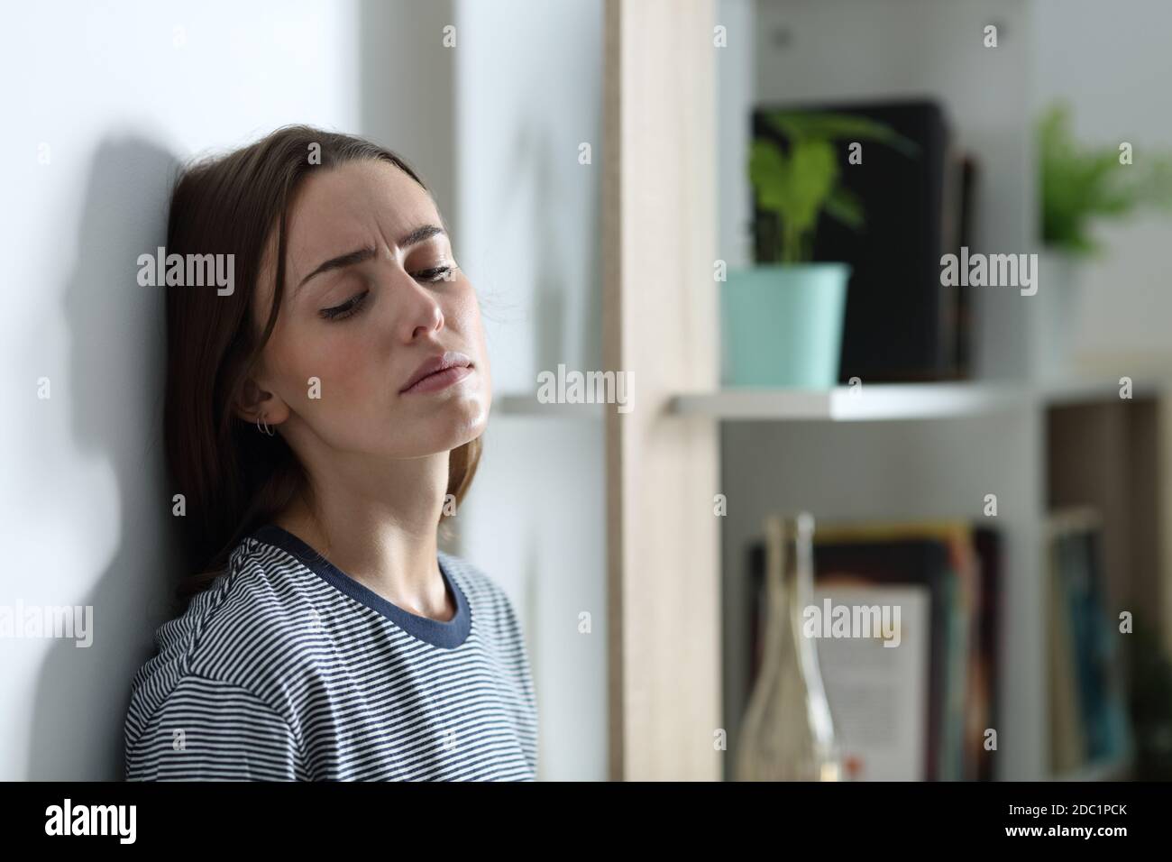Depressed woman complaining alone leaning on a wall at home Stock Photo ...