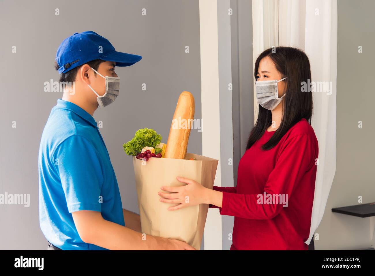 Asian young delivery man in uniform wear protective face mask he making ...