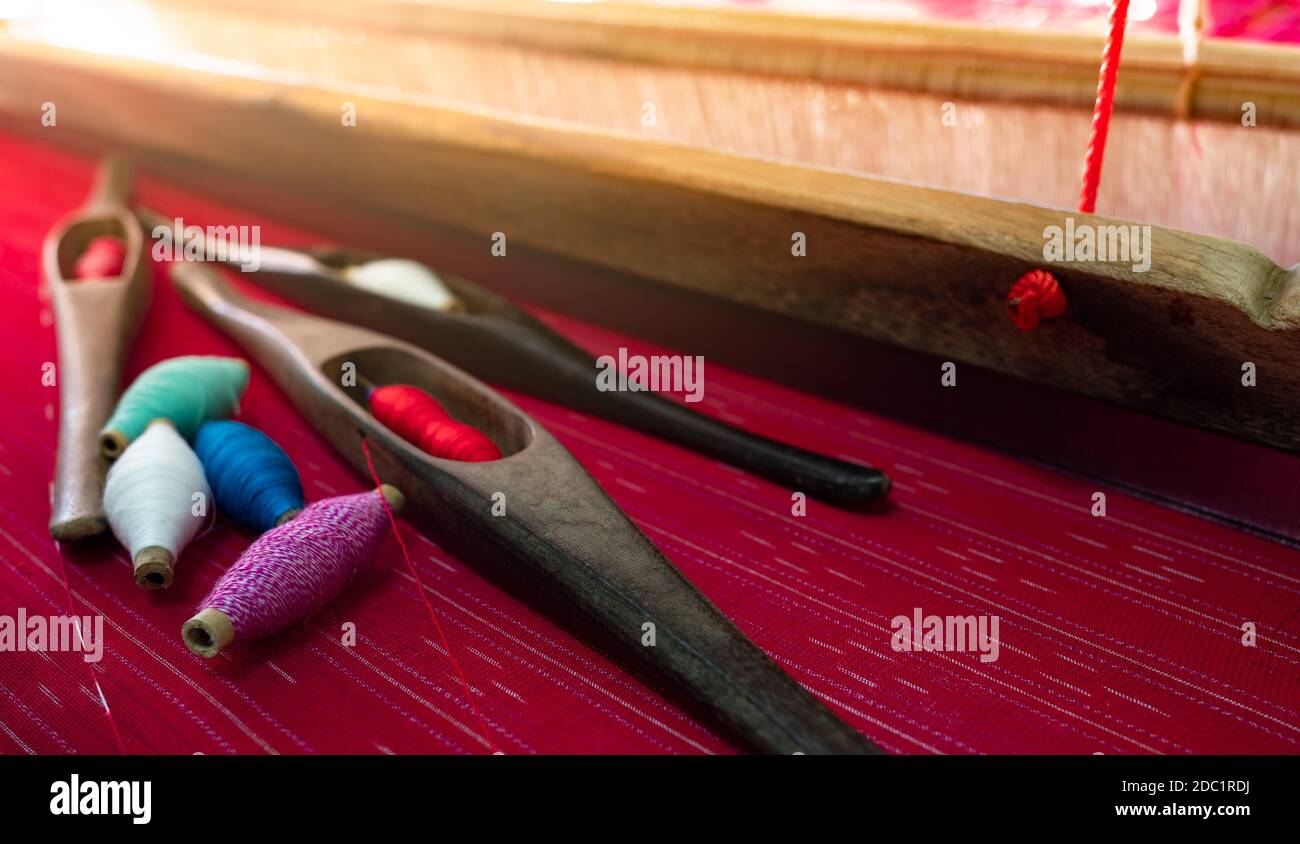 Selective focus on weaving shuttle tool on weaving machine. Red textile ...