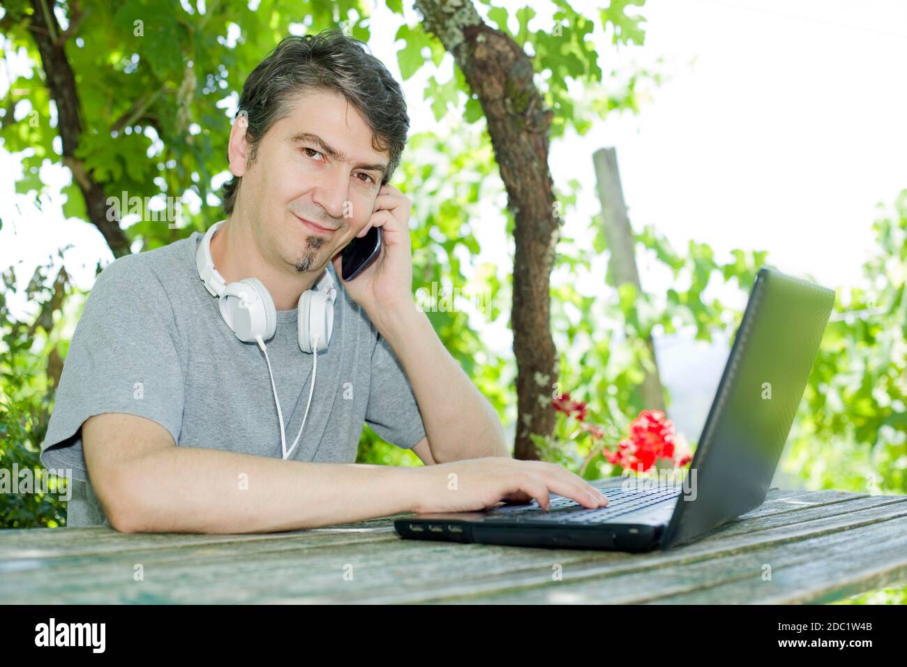 man sitting outdoor working with a laptop Stock Photo - Alamy