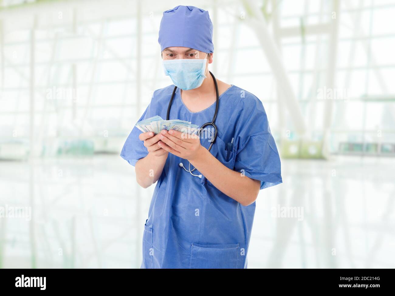Happy male doctor holding bank notes, at the hospital Stock Photo - Alamy