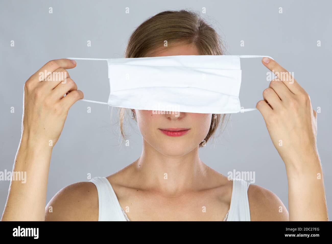 Blond woman holding face mask covering her eyes in front of her head ...