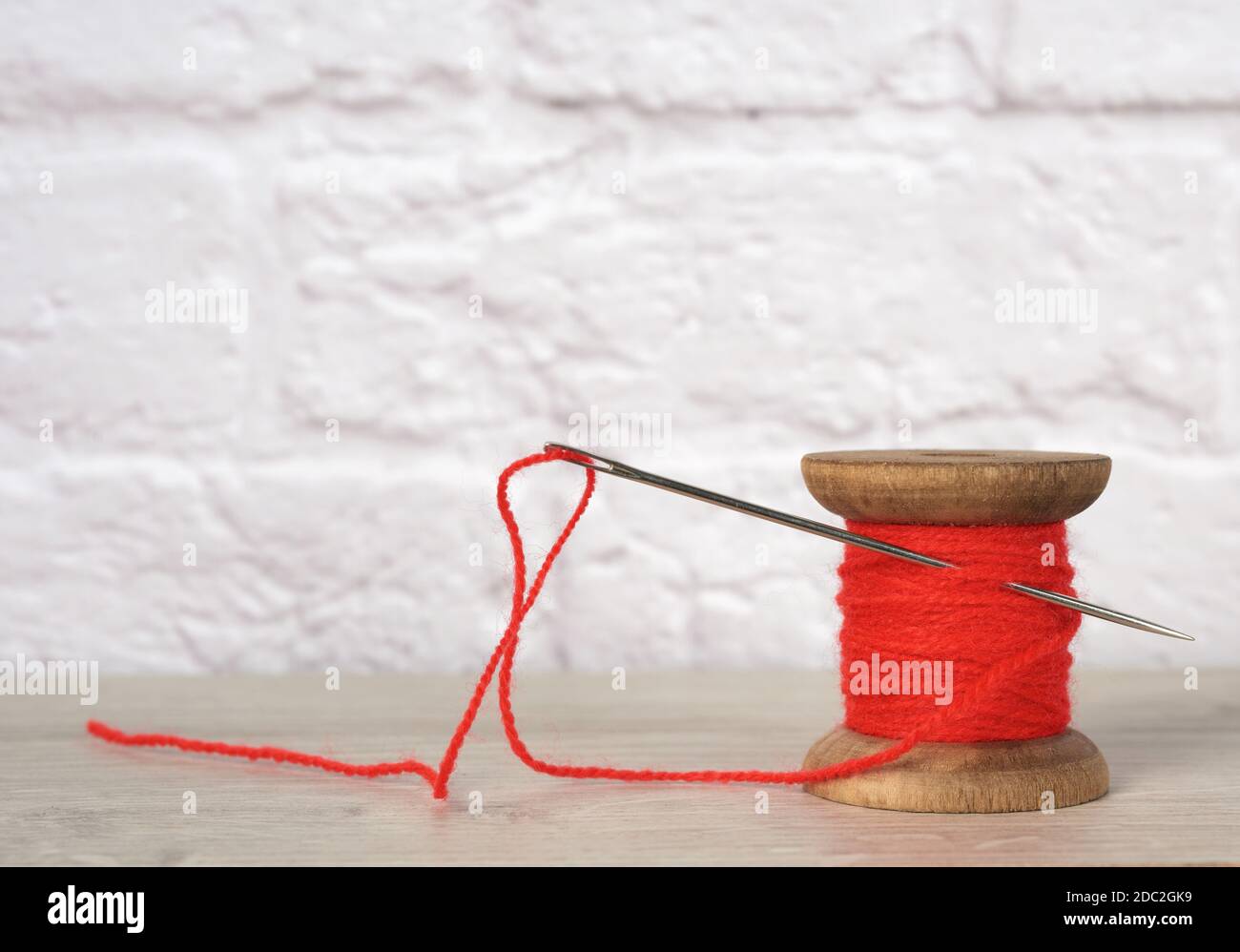 wooden spool with red wool thread on shelf, white wall, close up Stock ...