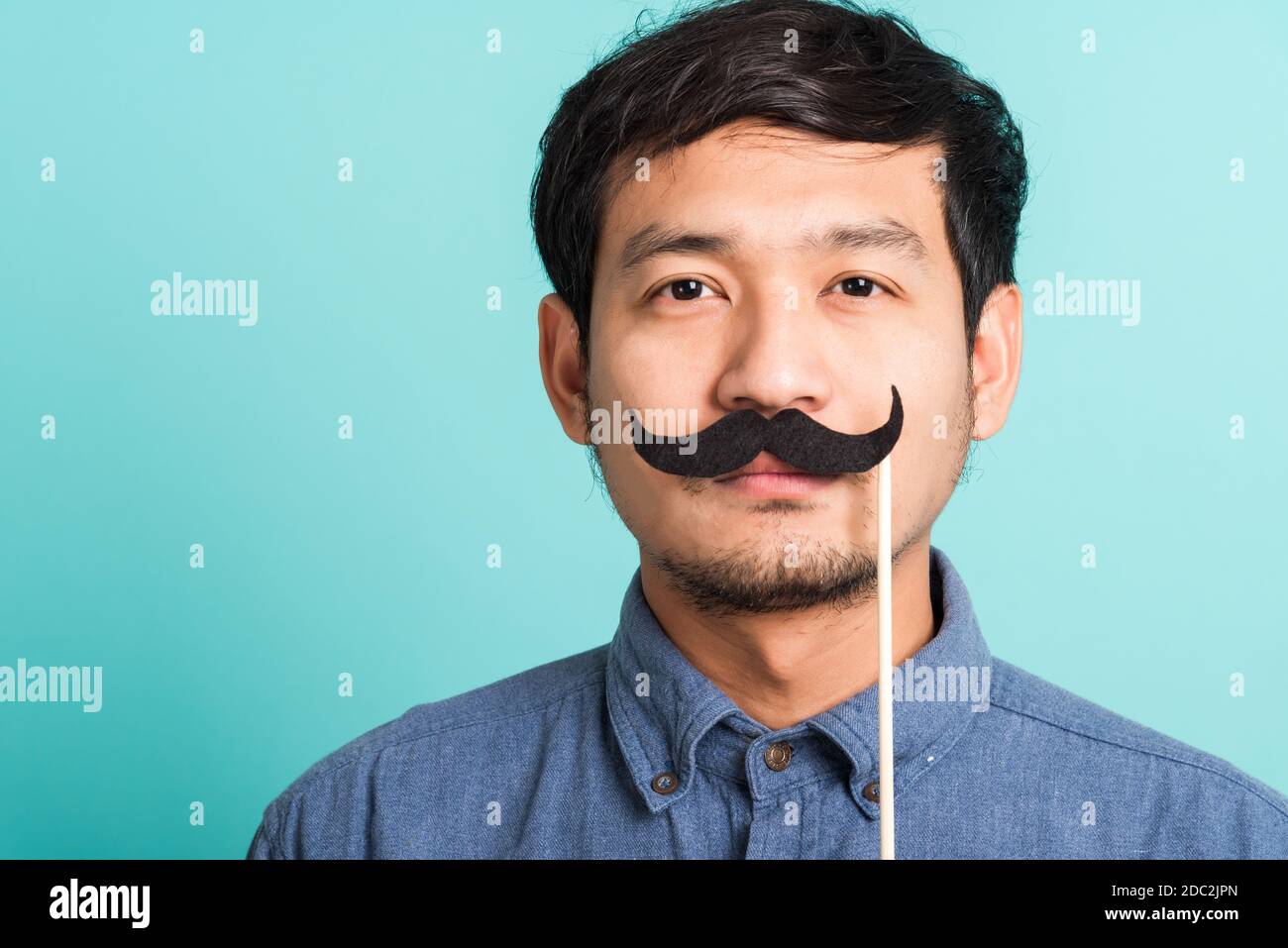 Portrait Asian happy handsome man posing he holding a funny mustache ...