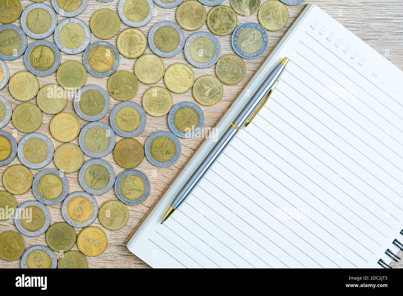 Top view coins with note pad on wood table using as financial concept ...
