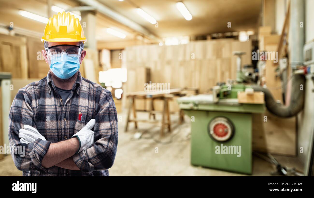 Carpenter worker in the carpentry workshop, wears helmet, goggles ...