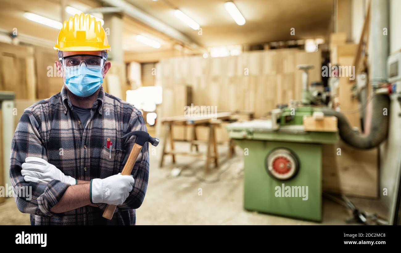 Carpenter worker in the carpentry workshop, wears helmet, goggles ...