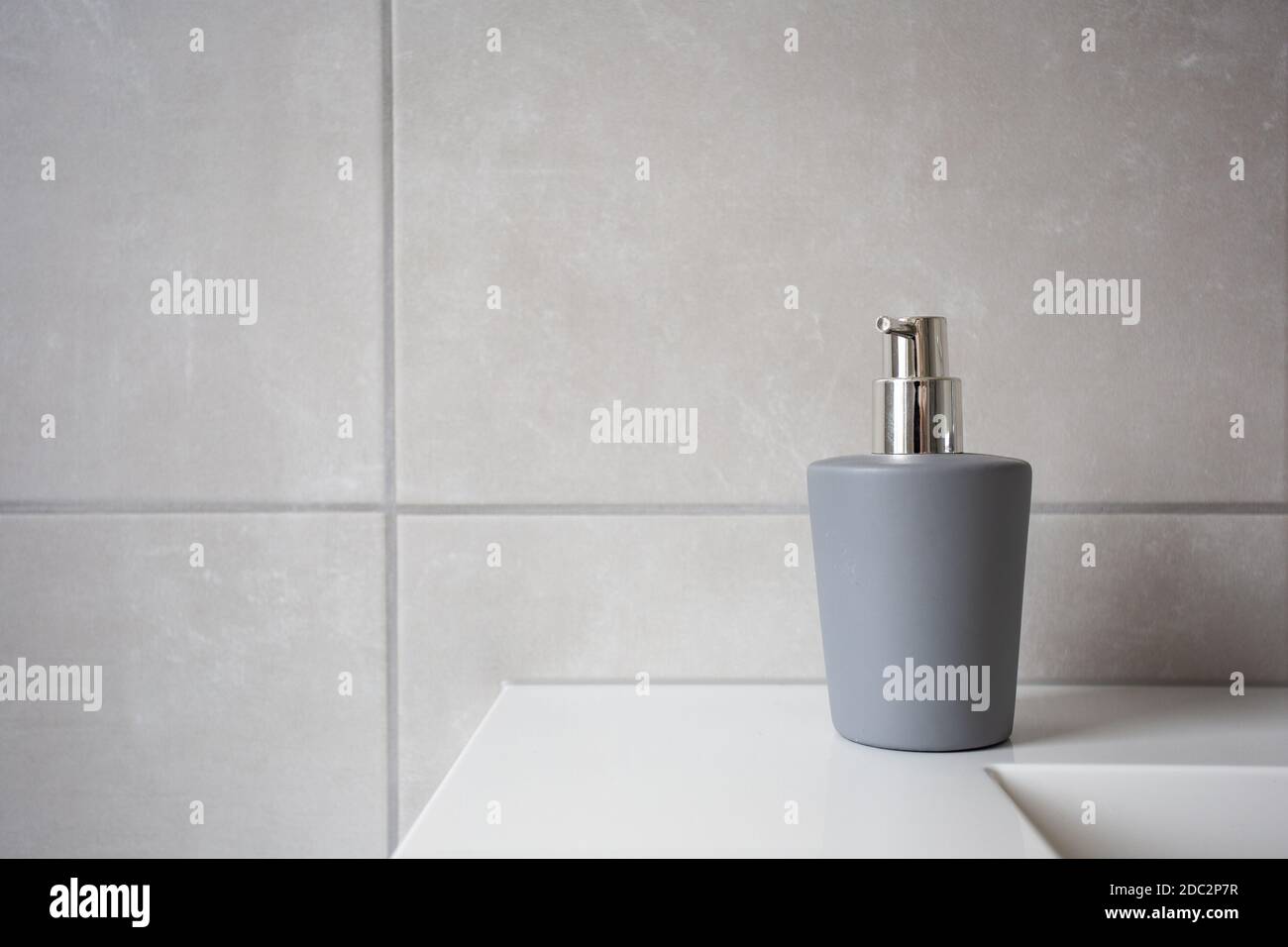 Gray soap dispenser for liquid soap, natural stone tiled bathroom ...