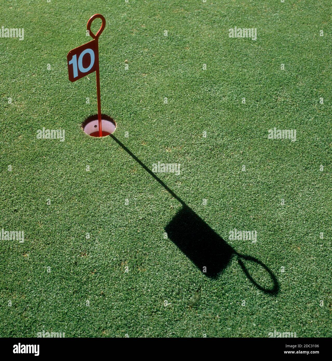 Number 10 marker, hole and long shadow in close mown grass turf of a ...