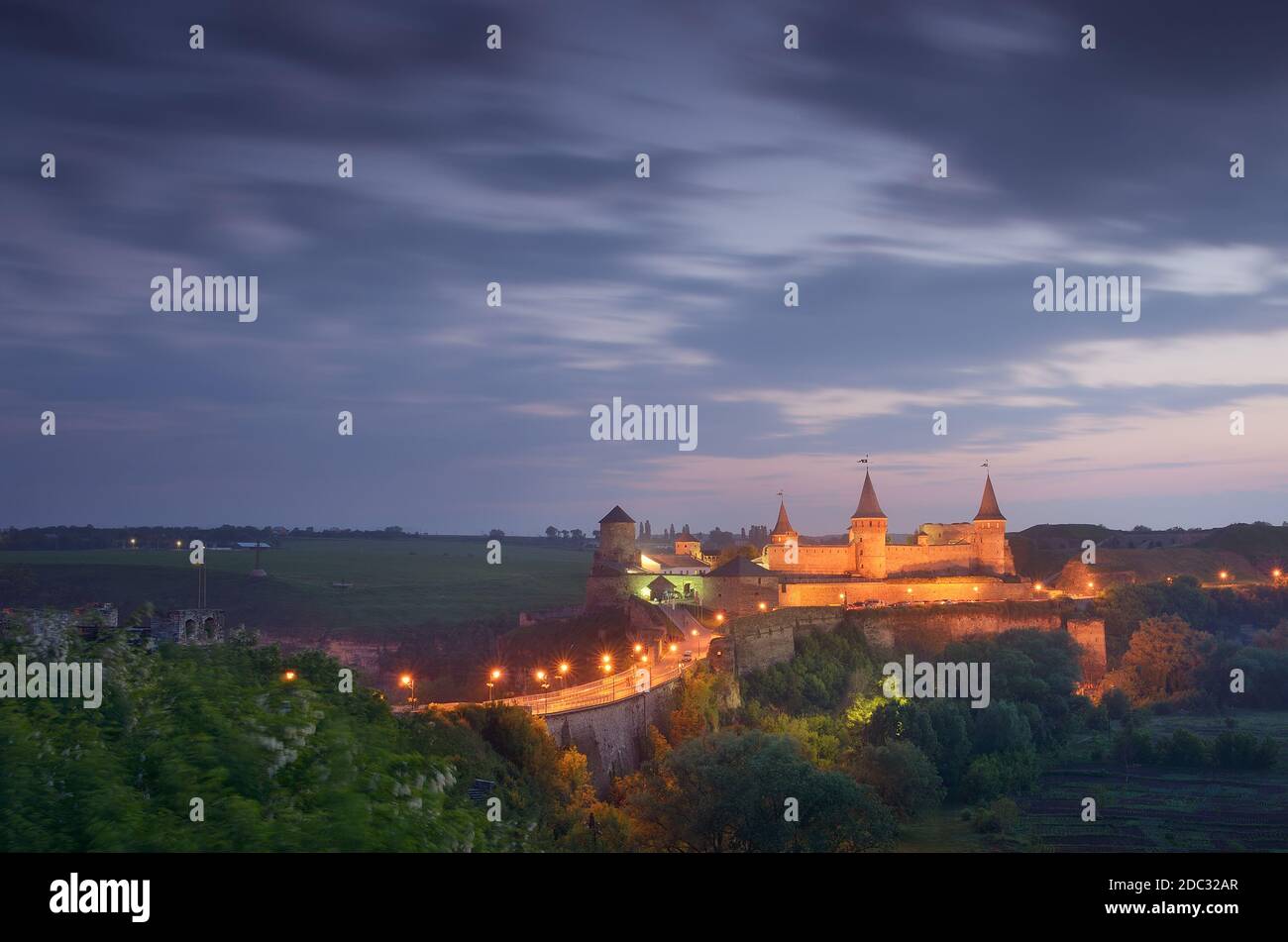 Night landscape with a road leading to the old castle. Illumination on ...
